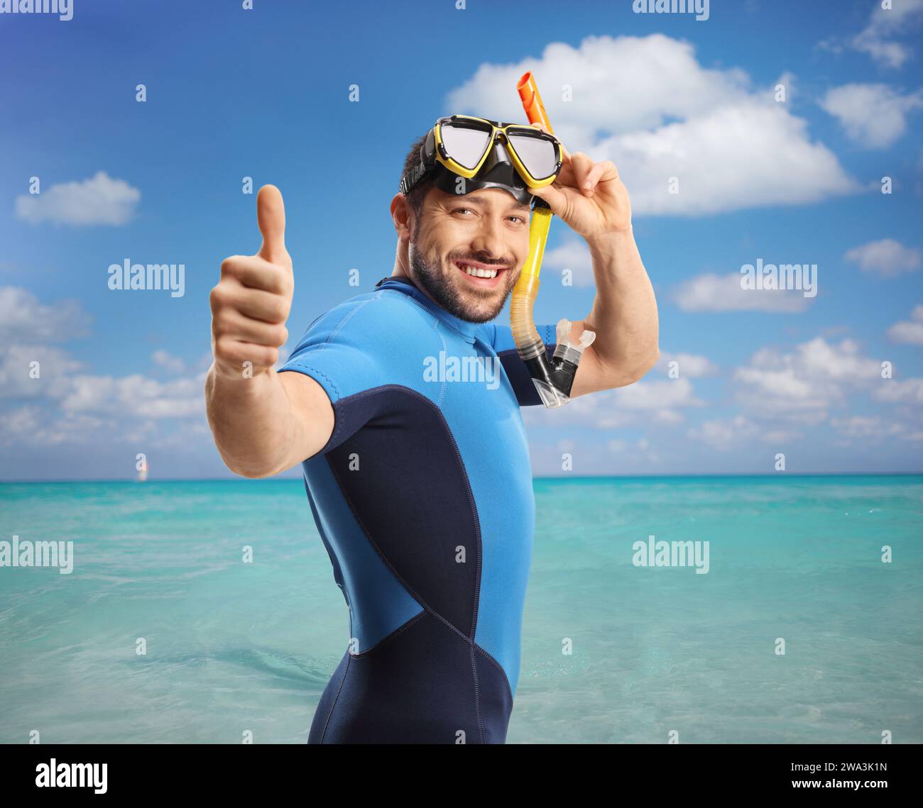 Young man in the sea wearing a diving suit and mask and gesturing ...