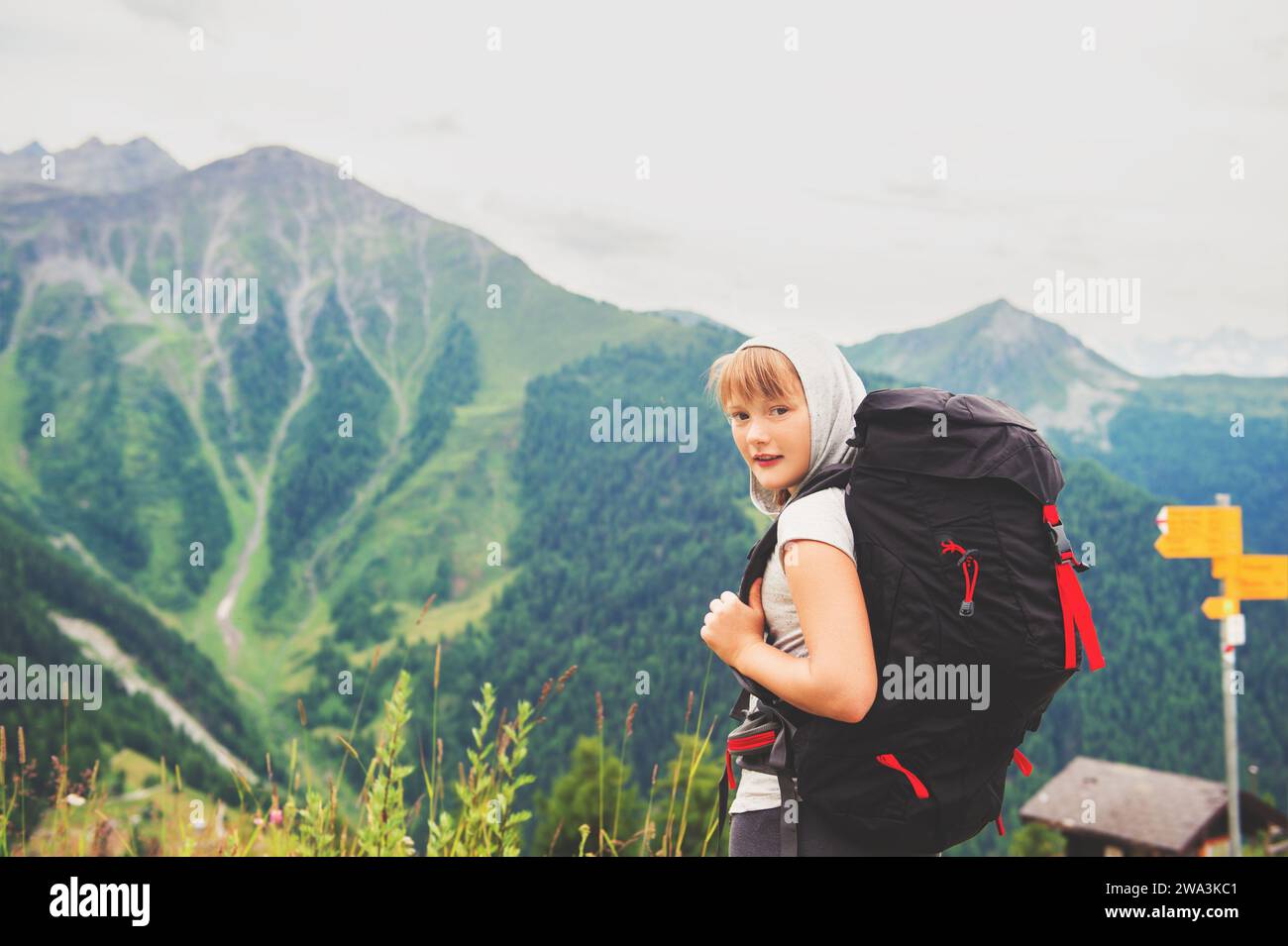 Happy little girl hiking in swiss Alps, wearing black backpack, travel ...