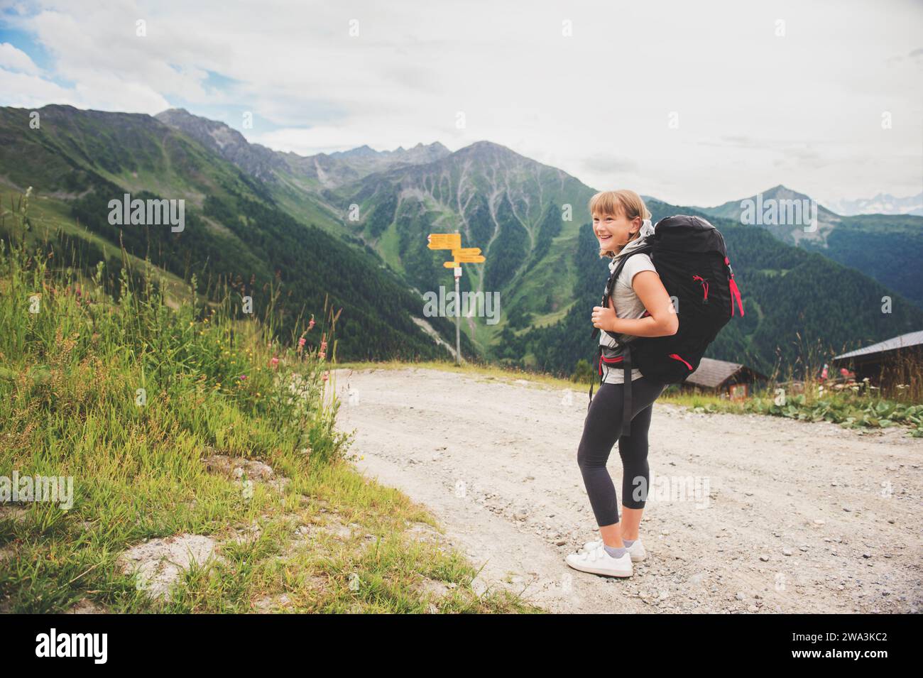 Happy little girl hiking in swiss Alps, wearing black backpack, travel ...