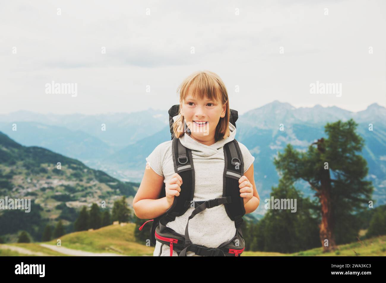 Happy little girl hiking in swiss Alps, wearing black backpack, travel ...