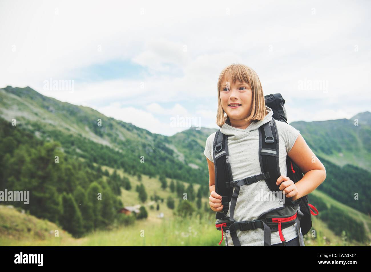 Happy little girl hiking in swiss Alps, wearing black backpack, travel ...