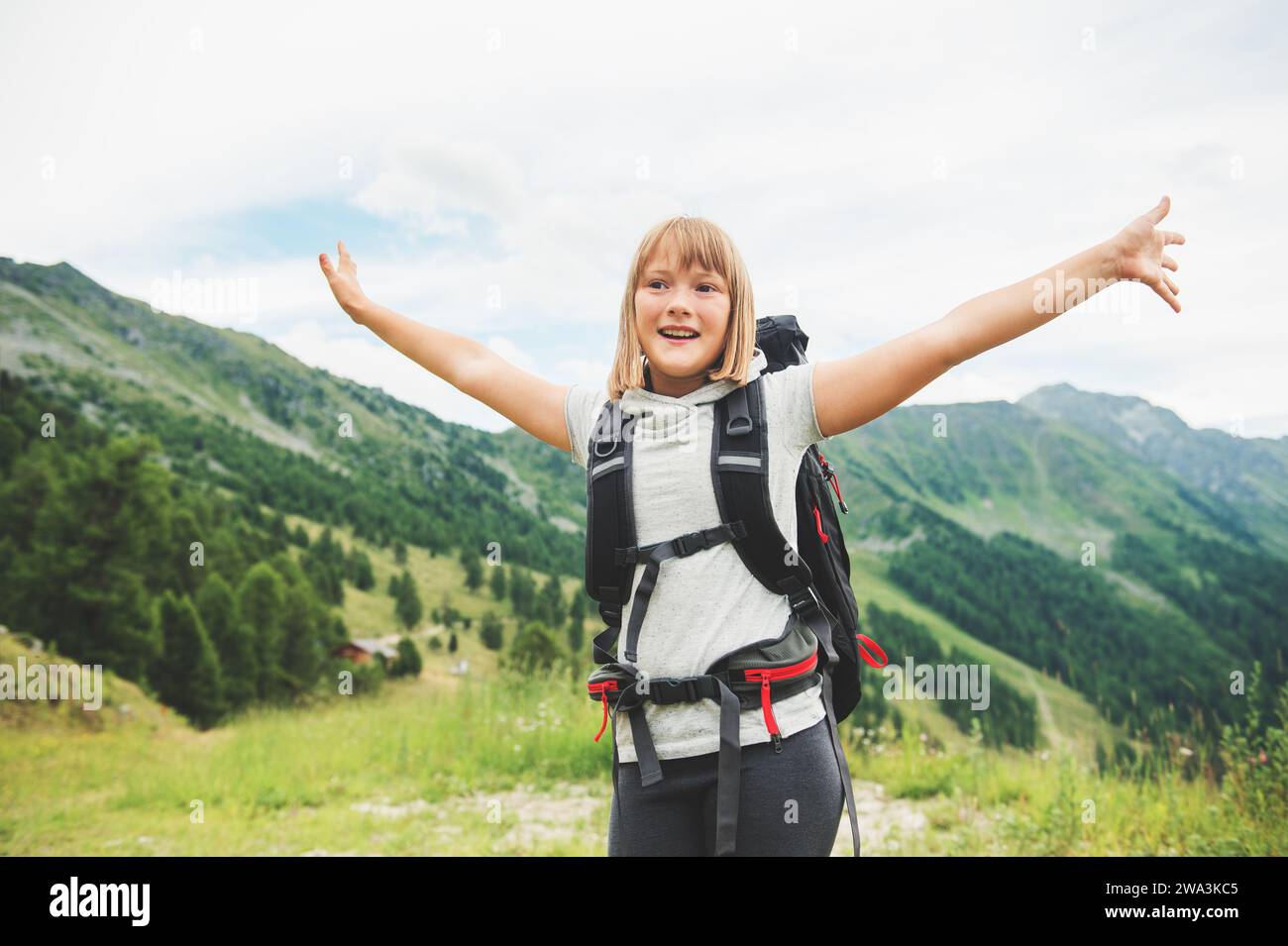 Happy little girl hiking in swiss Alps, wearing black backpack, travel ...