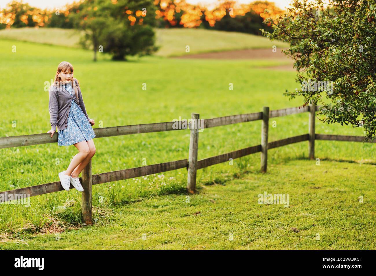 Pretty kid girl playing in a beautiful summer park at sunset, resting ...