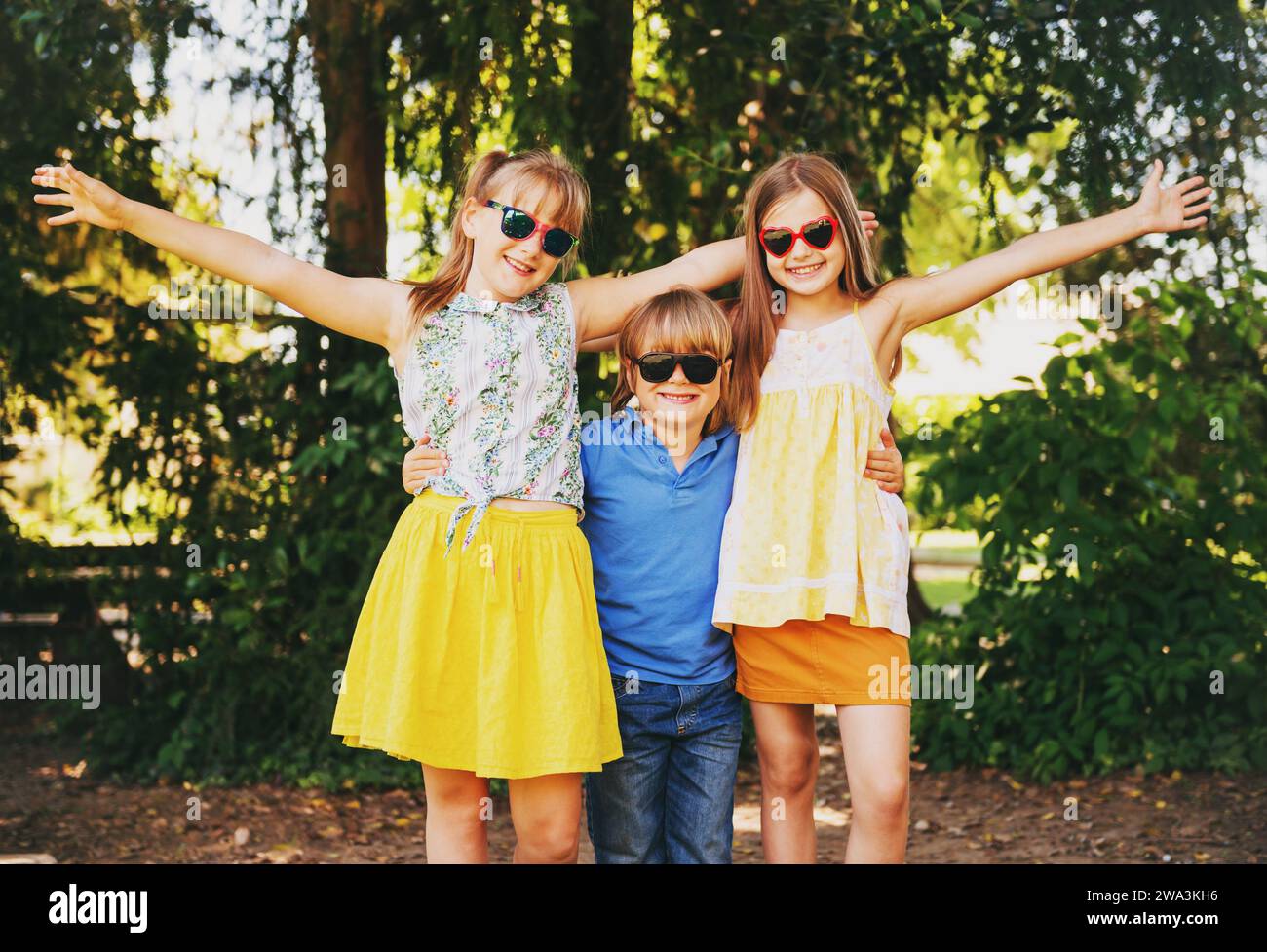 Outdoor portrait of 3 funny kids playing together in summer park. Happy ...