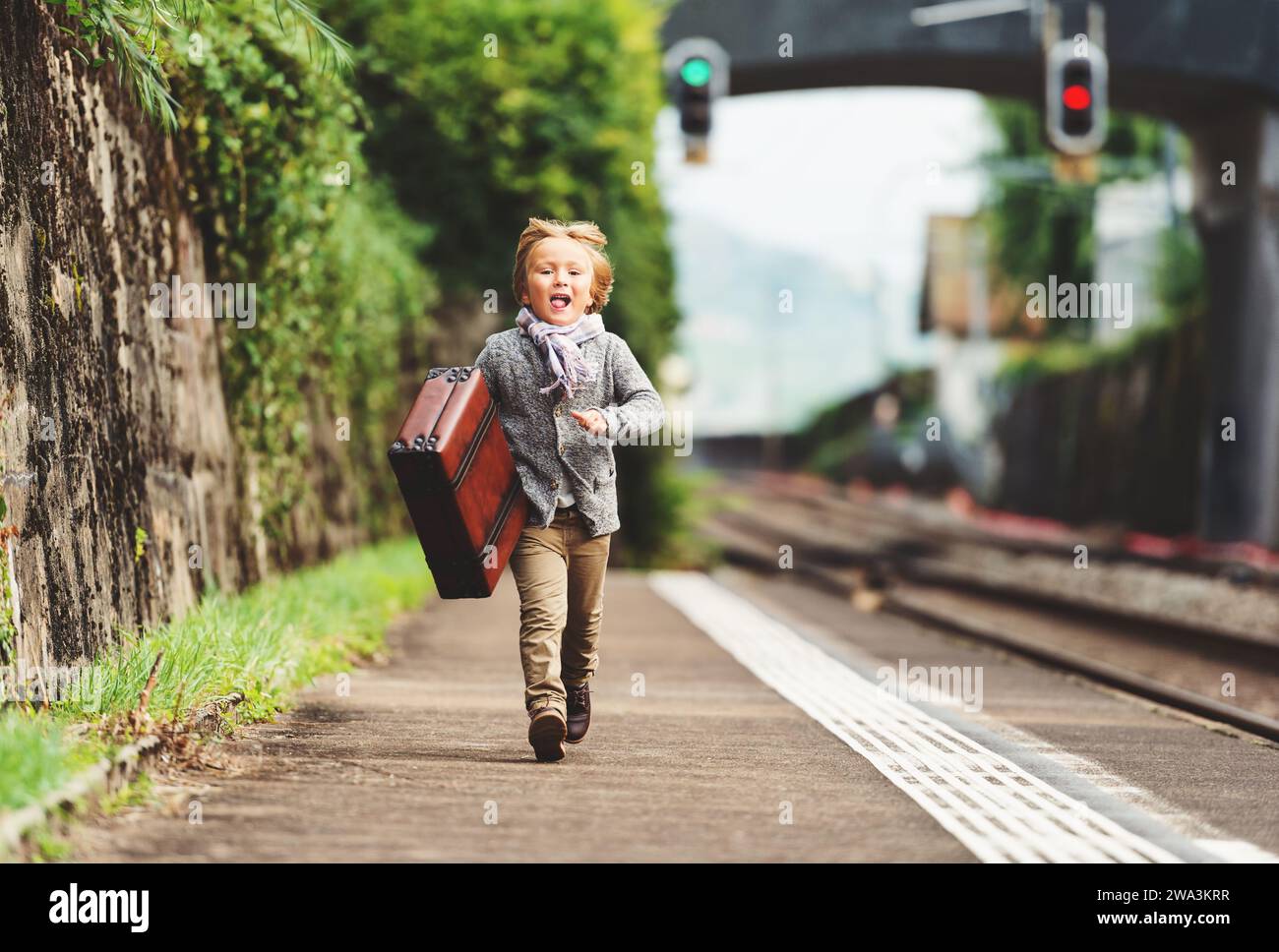 Outdoor portrait of cute little kid boy, run to the train station ...