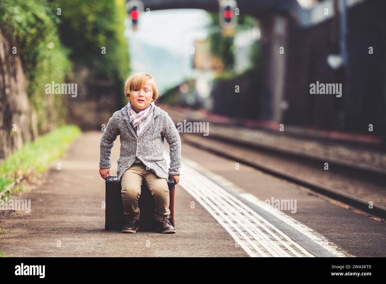 Adorable little boy on a railway station, waiting for the train with ...