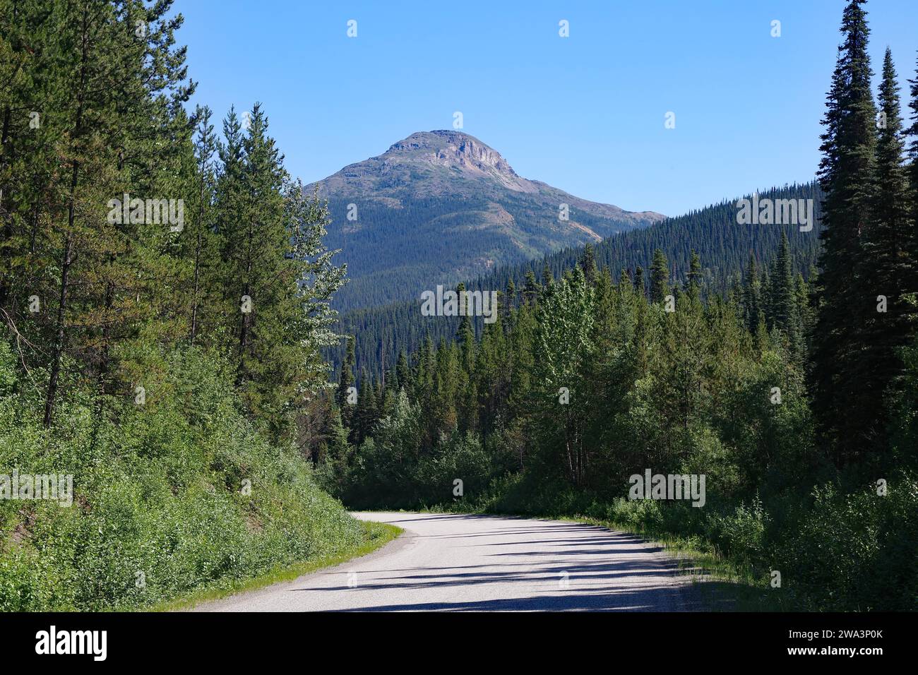 Narrow, traffic-free road leads through rugged mountain landscape ...