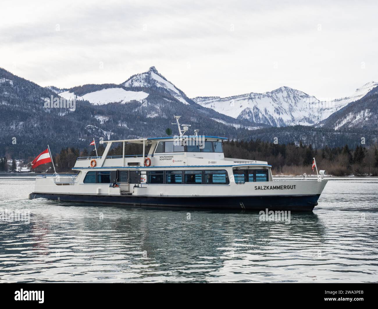 Snow-covered mountain peaks, excursion boat on Lake Wolfgangsee ...