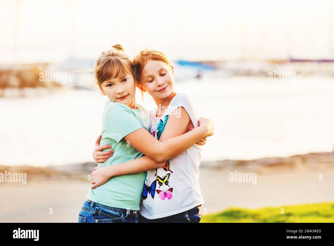 Two 9-10 year old girls playing together outside, hugging each other ...