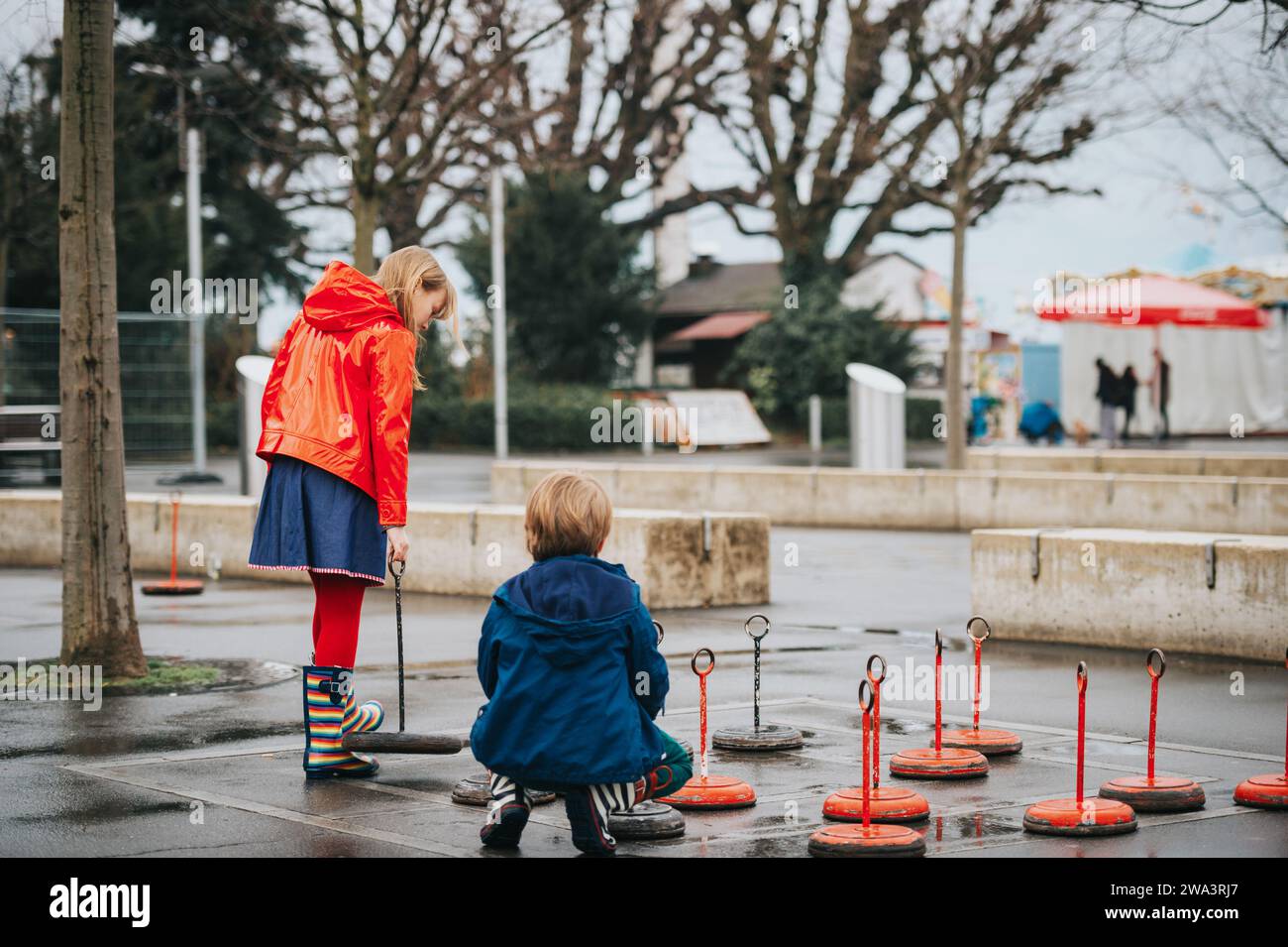 Group of two kids playing giant checkers on playground, wearing rain ...