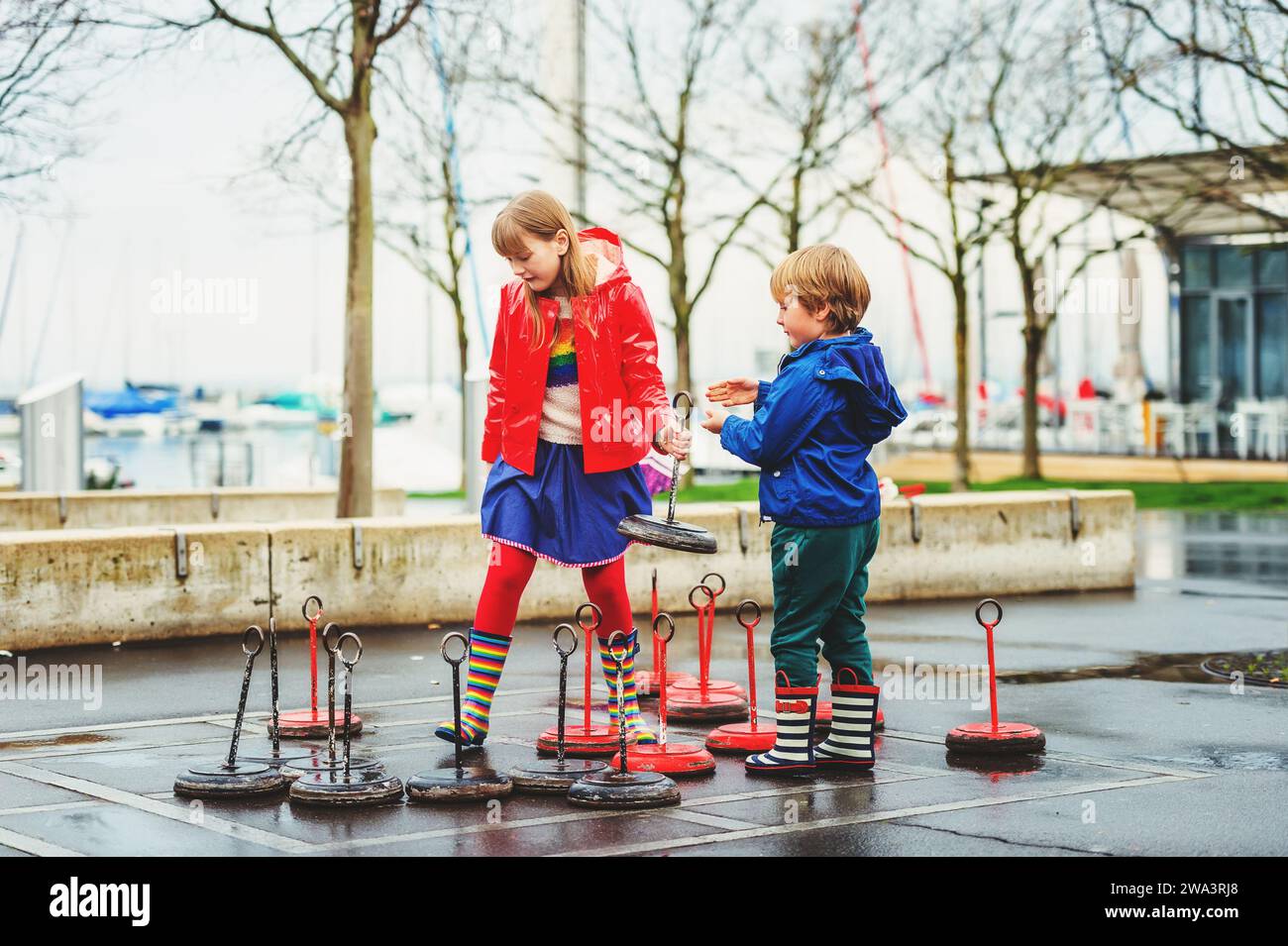 Group of two kids playing giant checkers on playground, wearing rain ...