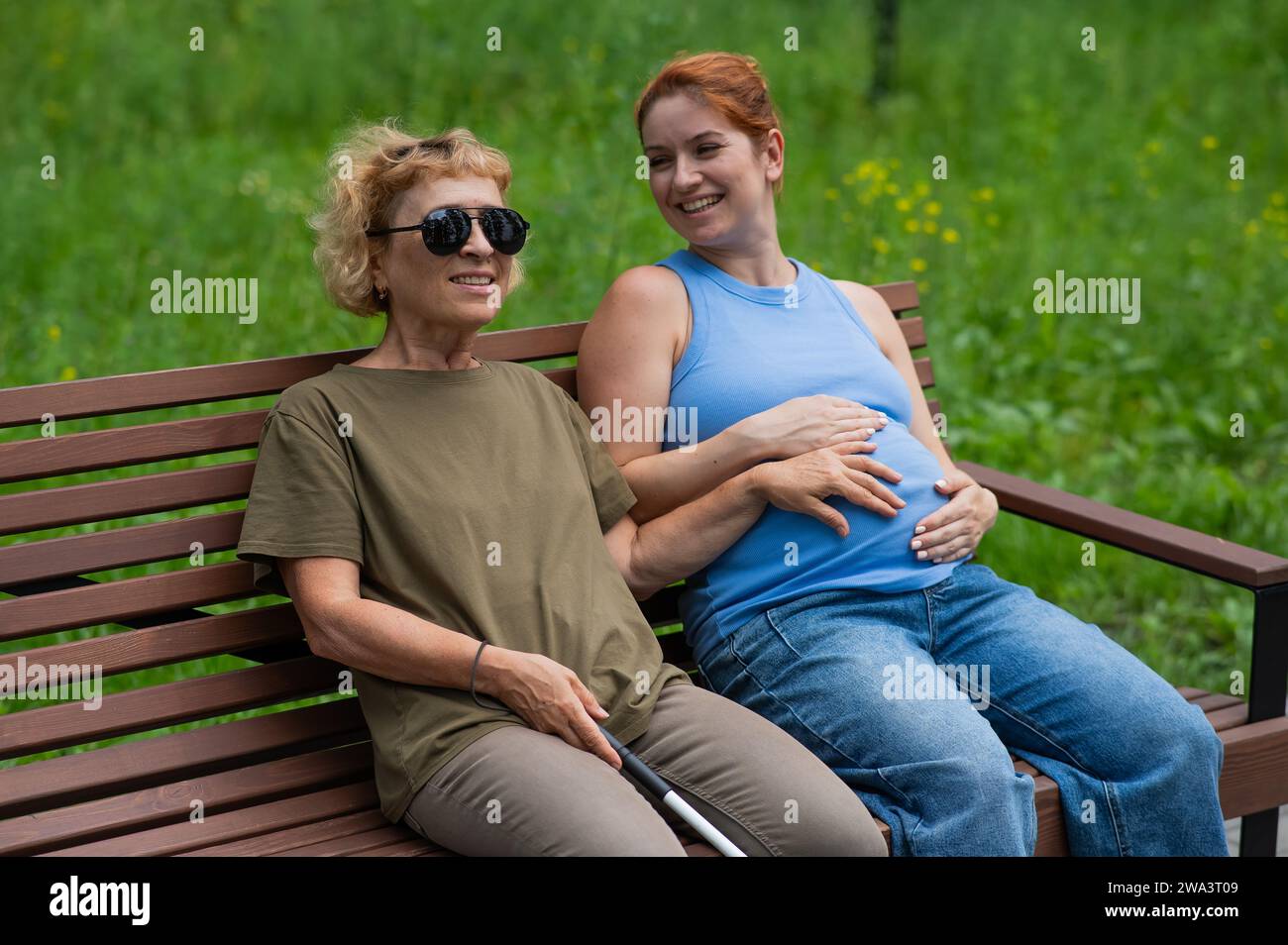An elderly blind woman holds her pregnant daughter by the belly while ...