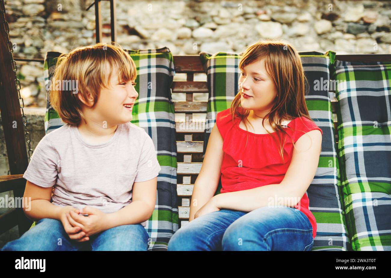 Two happy and laughing kids resting on swing bench Stock Photo - Alamy