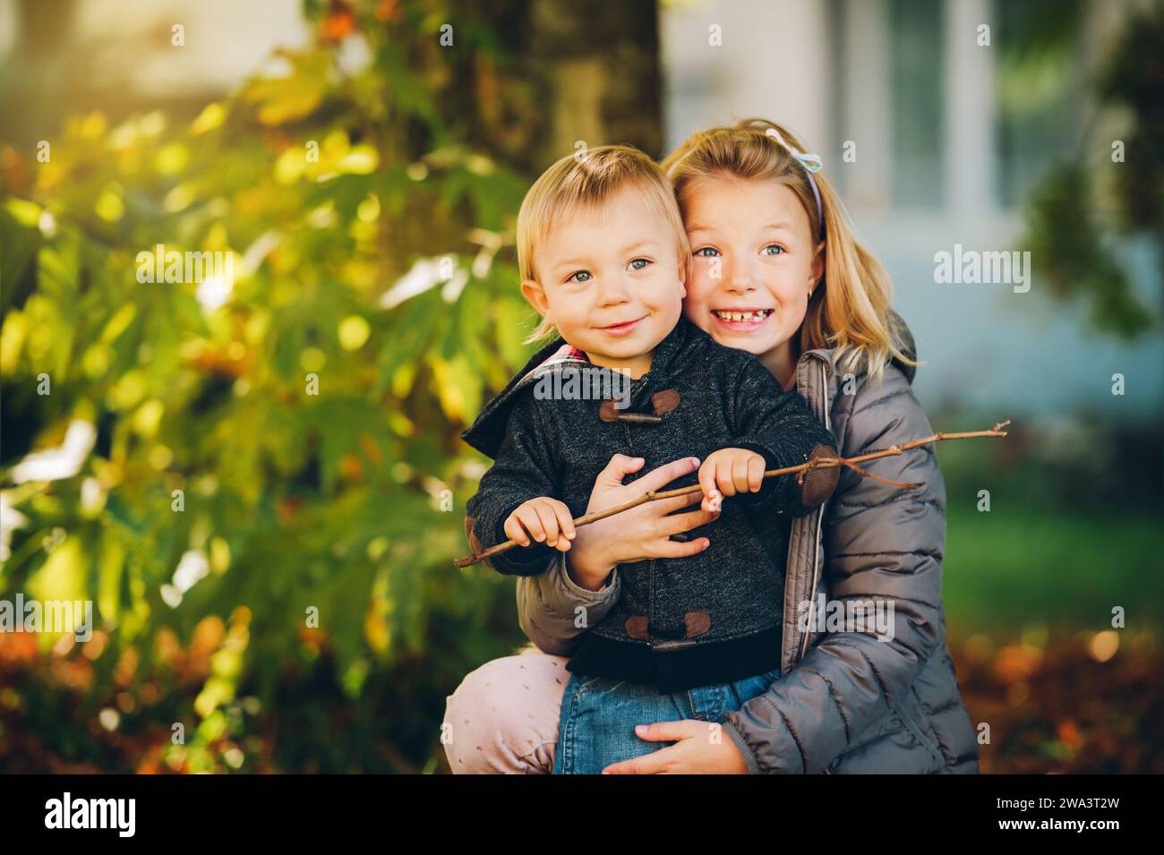 Outdoor autumn portrait of two happy kids, big sister and small brother ...