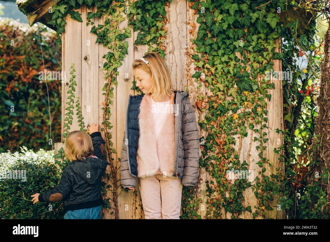 Two kids playing together in beautiful autumn garden, wearing warm ...
