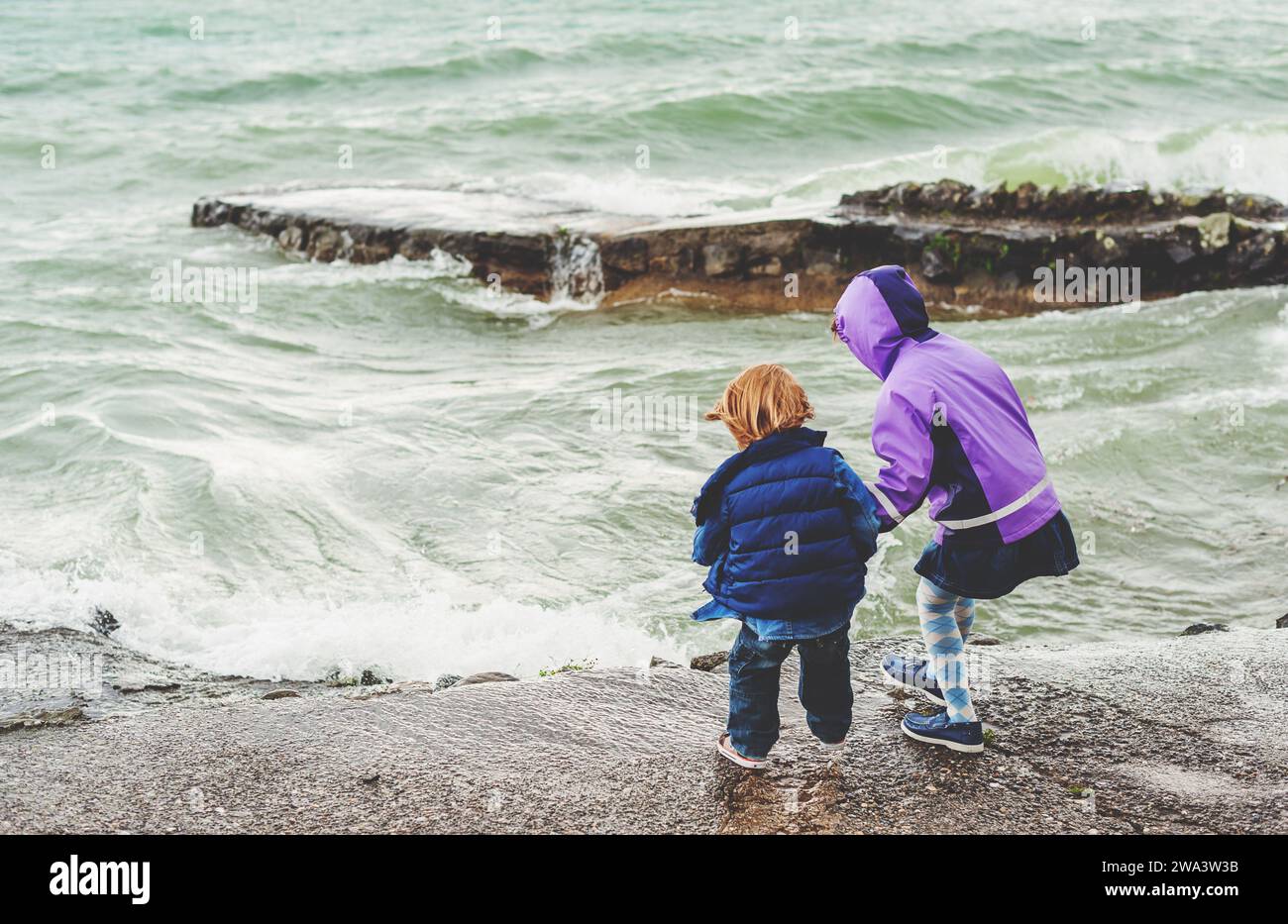 Group of two little kids playing by lake Geneva on a very windy day ...