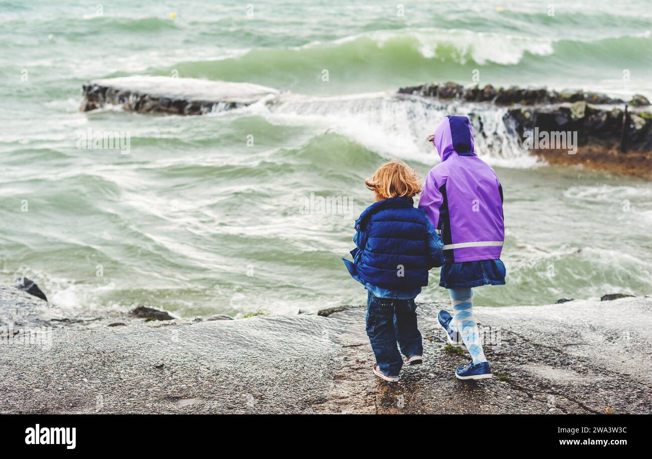 Group of two little kids playing by lake Geneva on a very windy day ...