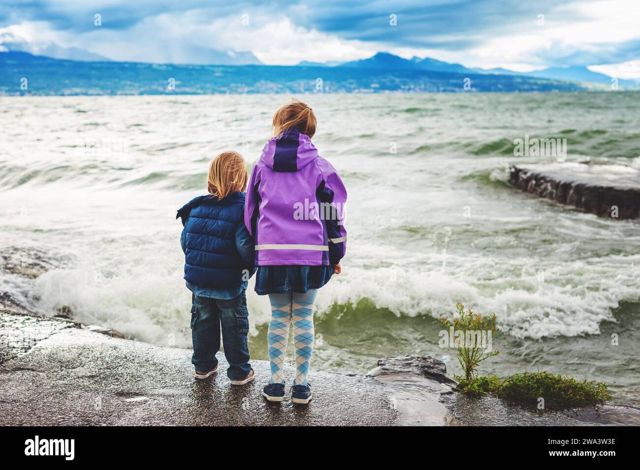 Group of two little kids playing by lake Geneva on a very windy day ...