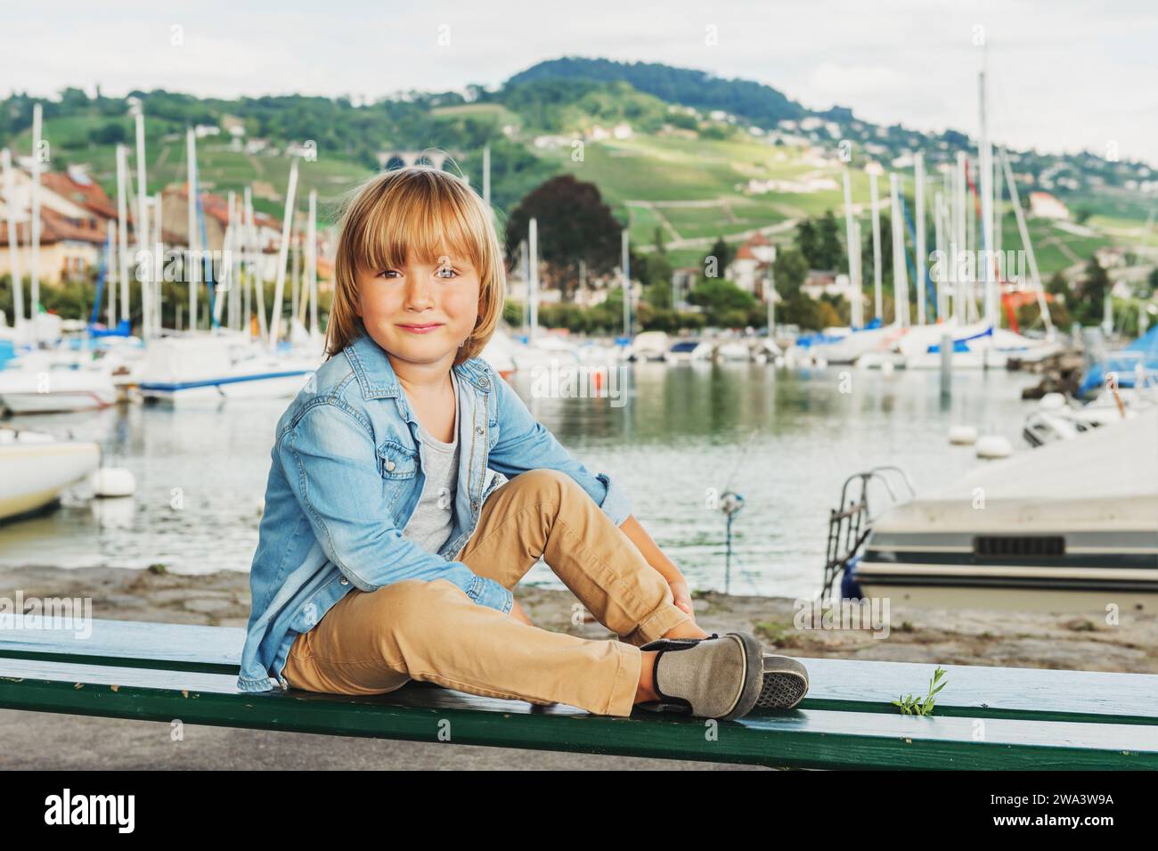 Outdoor portrait of adorable little boy resting on the bench in a ...