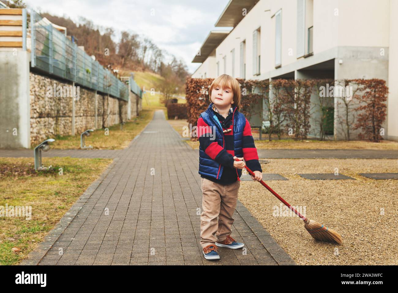 Cute little boy sweeping the backyard on a early spring day Stock Photo ...