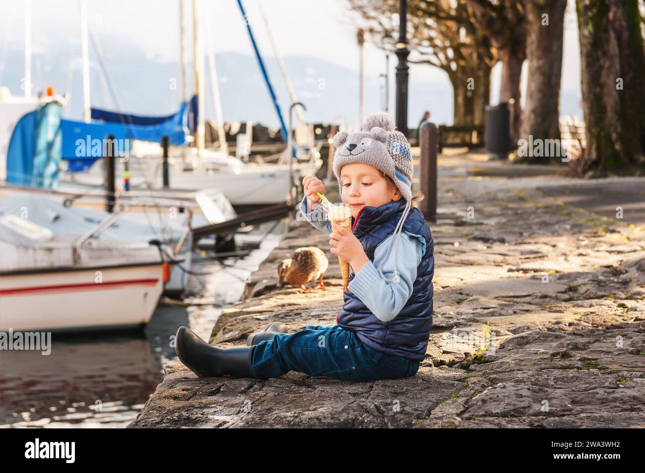 Adorable little boy eating ice cream outdoors on a cold weather Stock ...