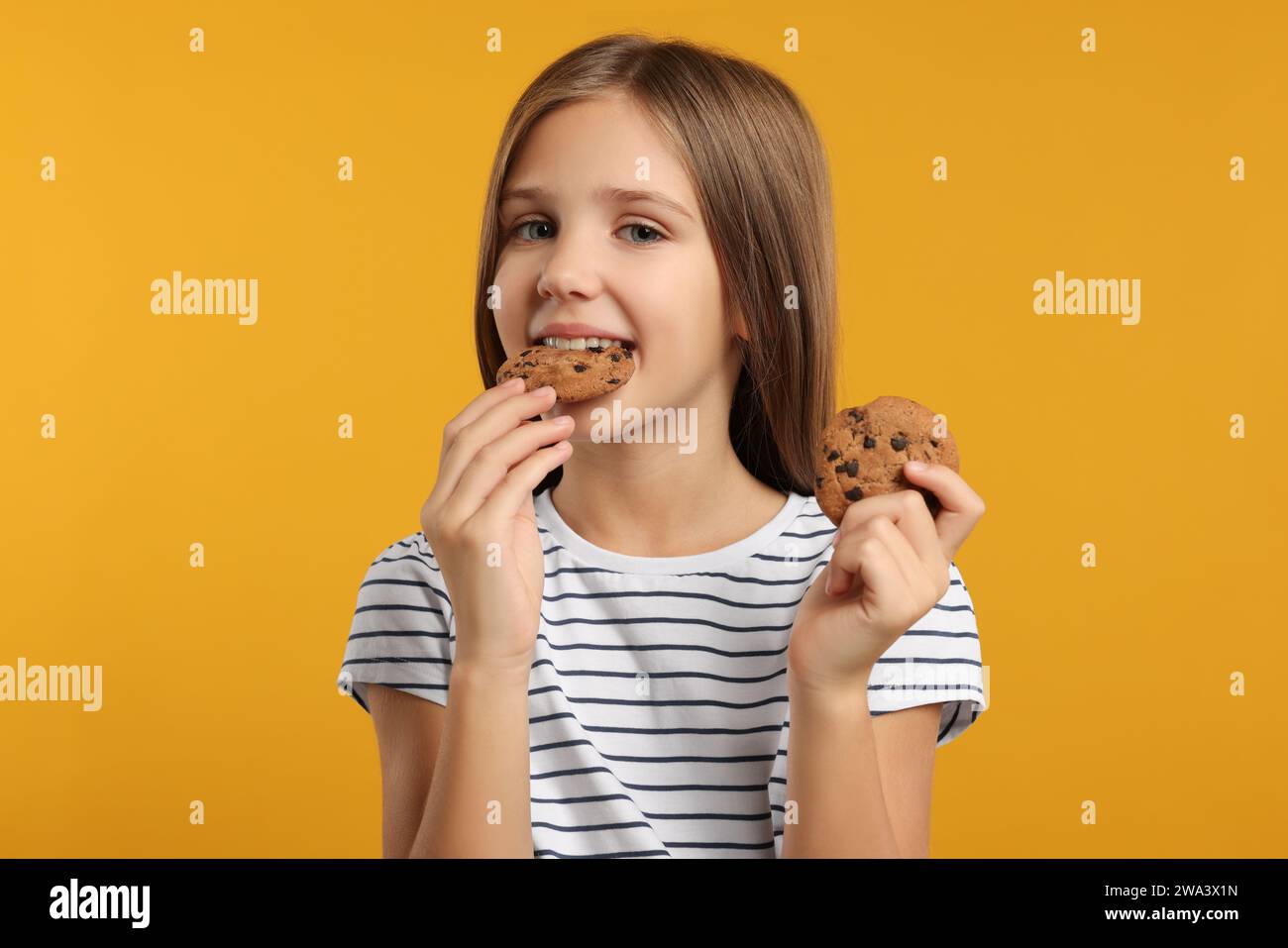Cute Girl Eating Chocolate Chip Cookies On Orange Background Stock