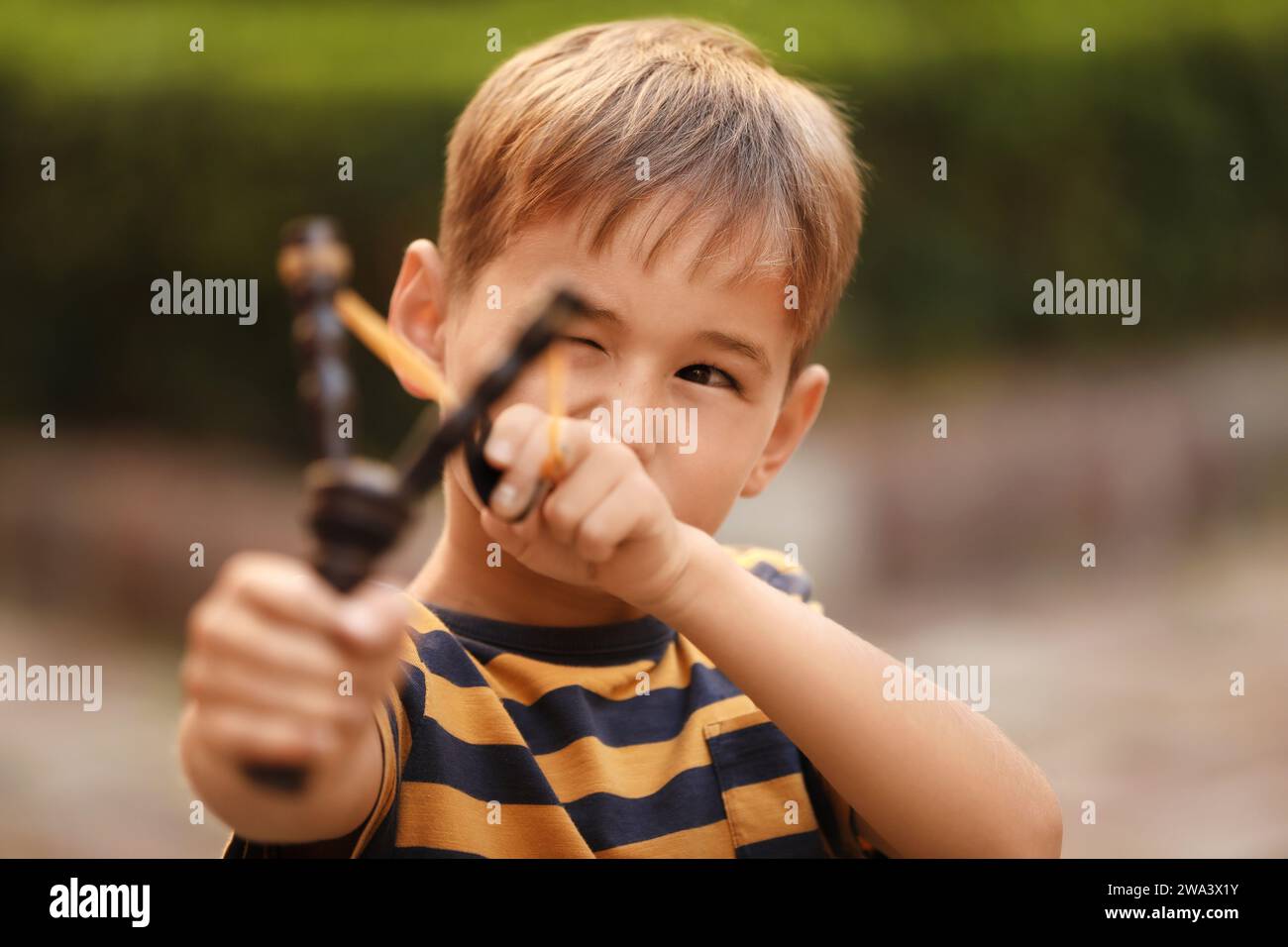 Little boy playing with slingshot in park Stock Photo - Alamy