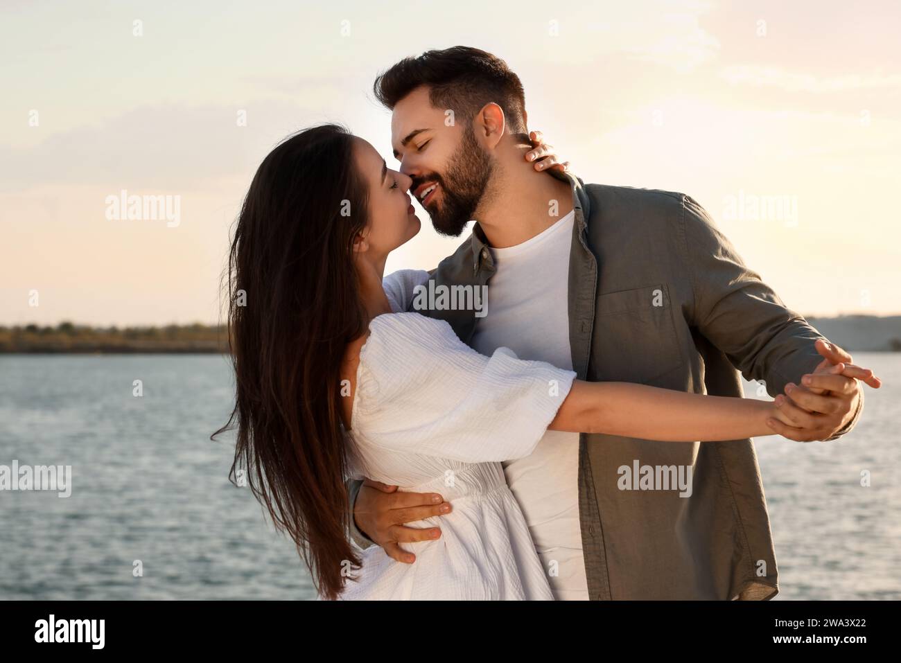 Happy couple dancing and kissing near river Stock Photo - Alamy