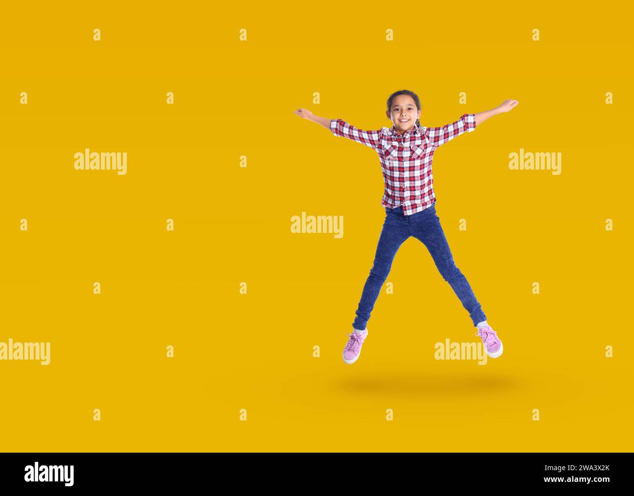 Cute girl jumping on golden background, space for text Stock Photo - Alamy
