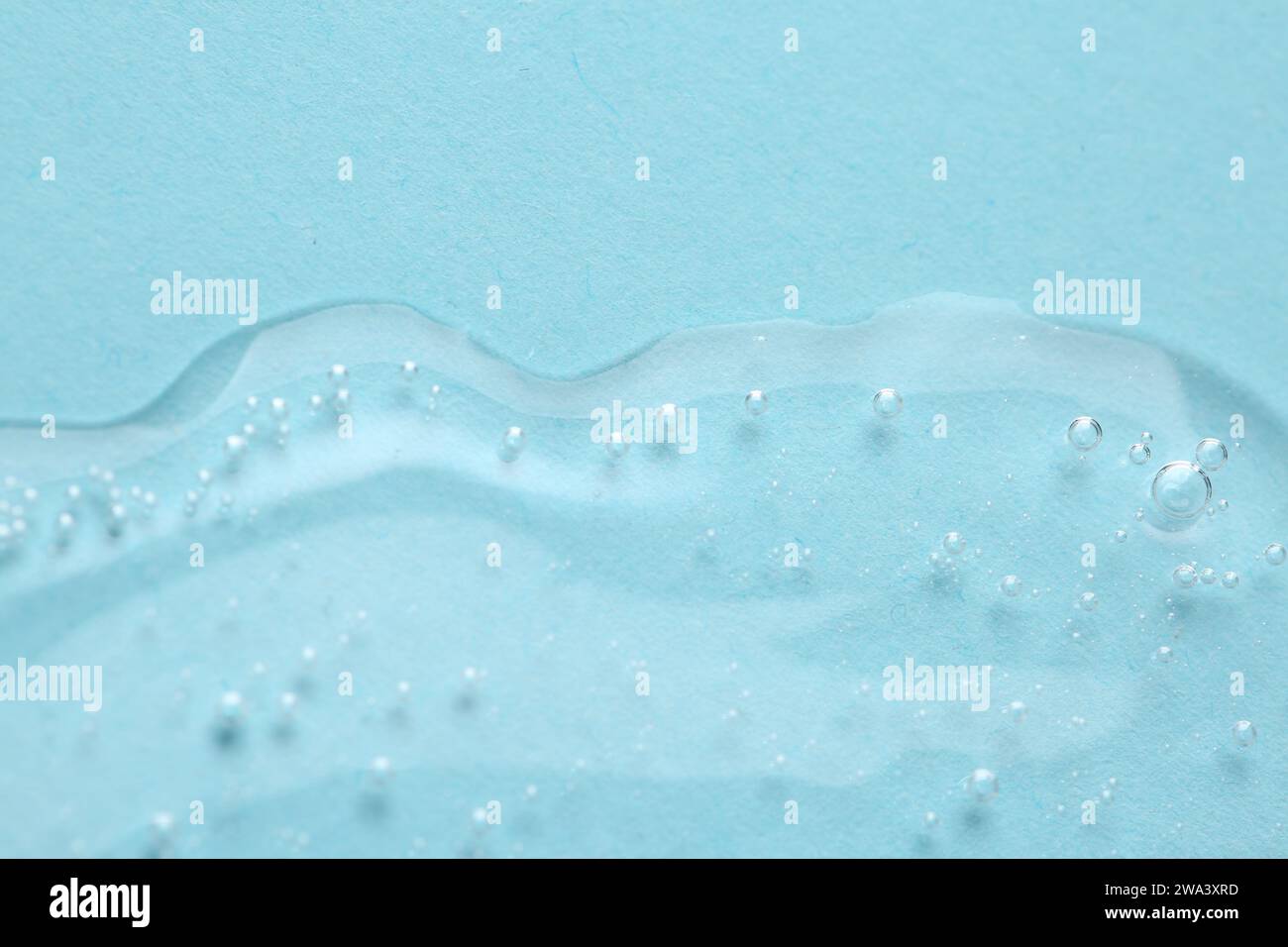 Clear cosmetic serum on light blue background, top view. Space for text ...