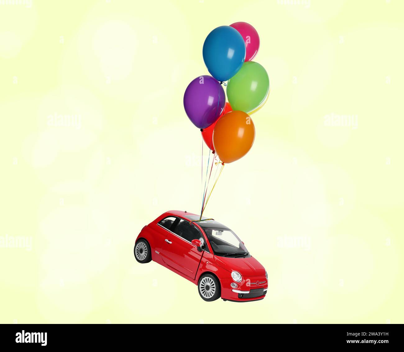 Many balloons tied to toy car flying on light yellow background Stock ...