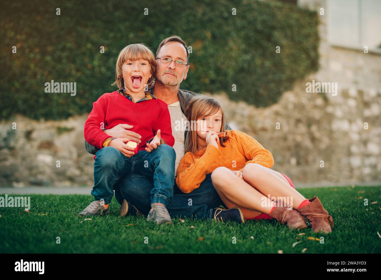 Outdoor portrait of happy father with two kids, boy and girl resting ...