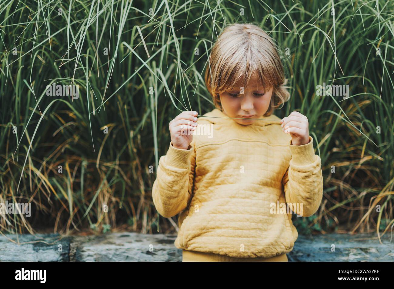 Outdoor fashion portrait of cute little boy wearing yellow hoody ...