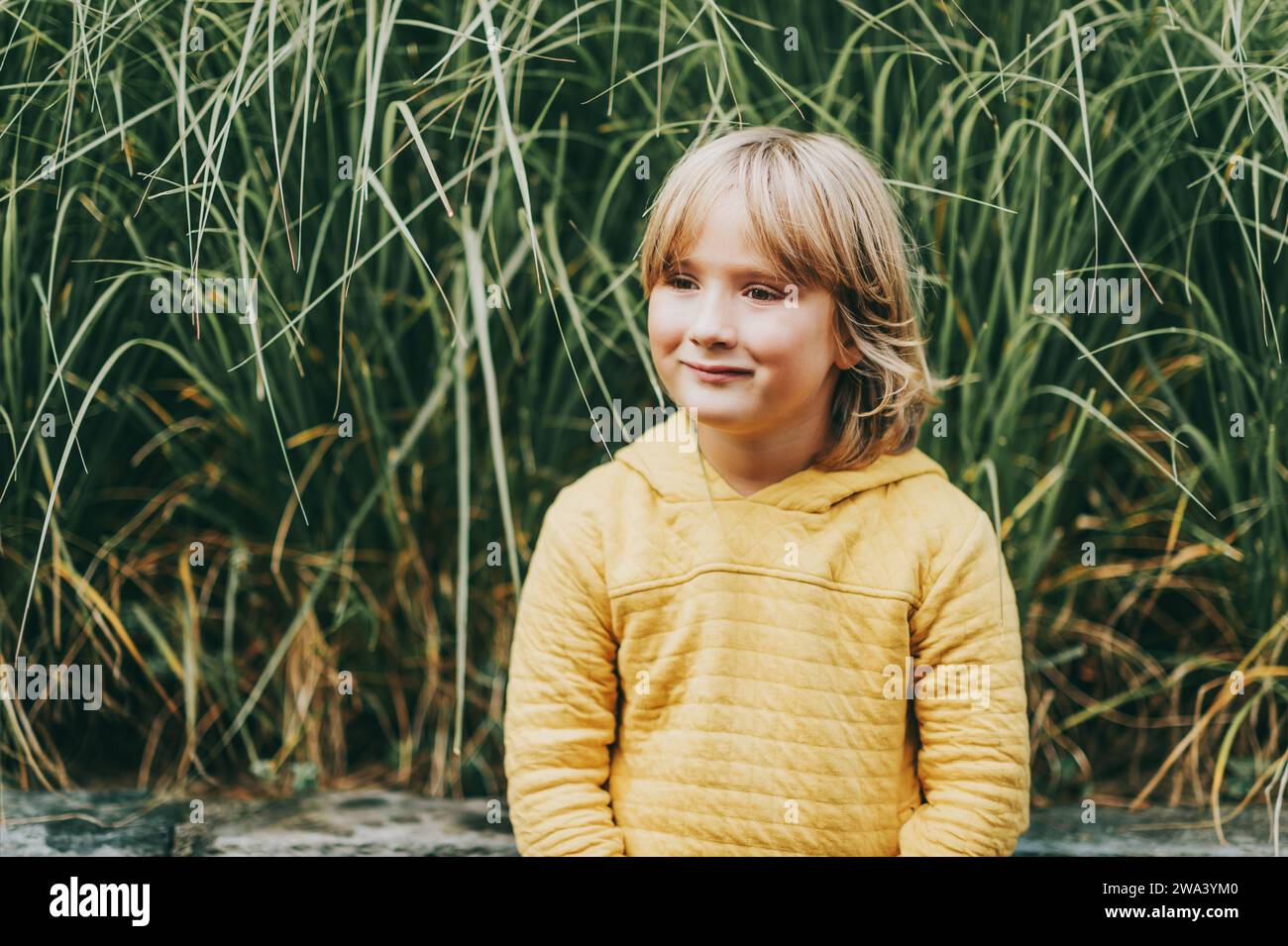 Outdoor fashion portrait of cute little boy wearing yellow hoody ...