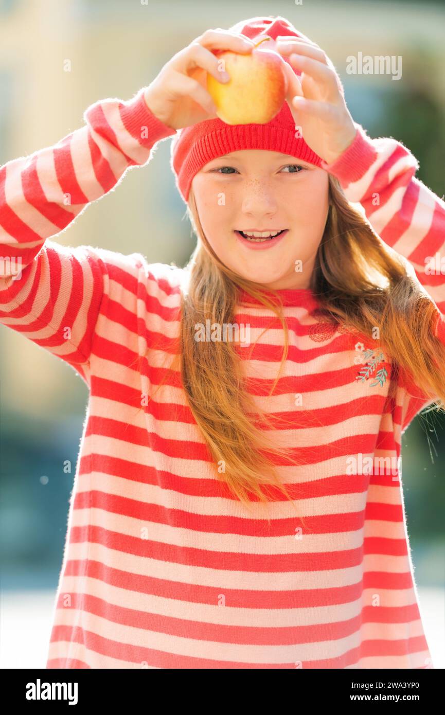 Outdoor portrait of young 9-10 year girl, wearing red stripe hat and ...