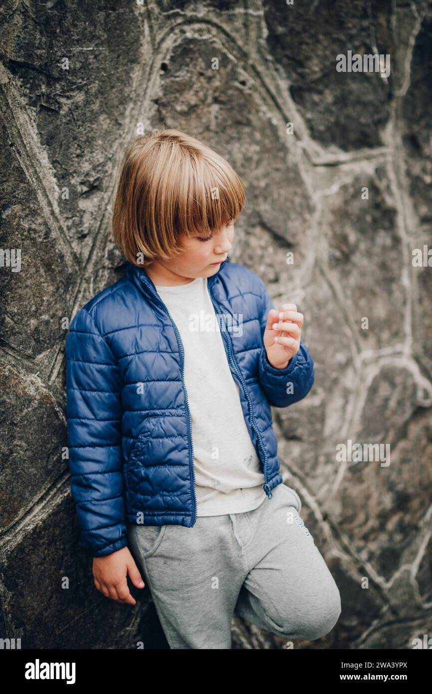 Outdoor fashion portrait of stylish kid boy wearing blue padded jacket ...