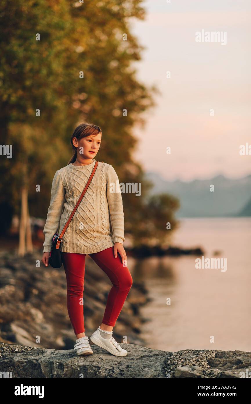 Outdoor portrait of cute preteen girl admiring nice sunset over lake ...
