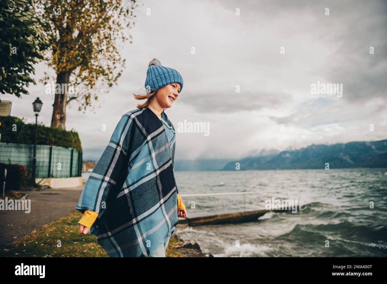 Sweet little girl playing by the lake on a very windy day, wearing blue ...