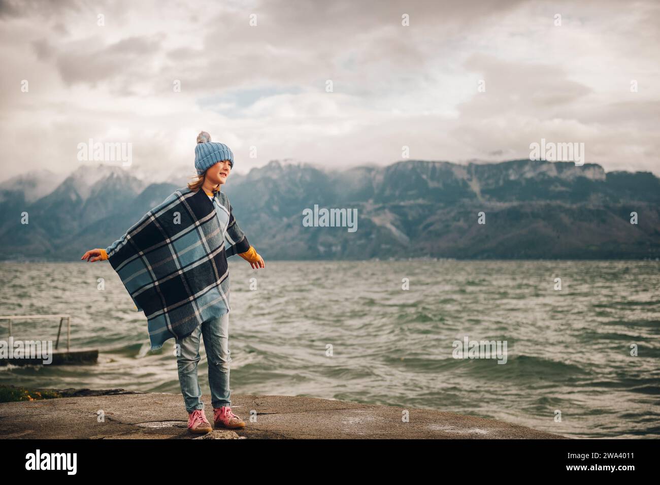 Sweet little girl playing by the lake on a very windy day, wearing blue ...