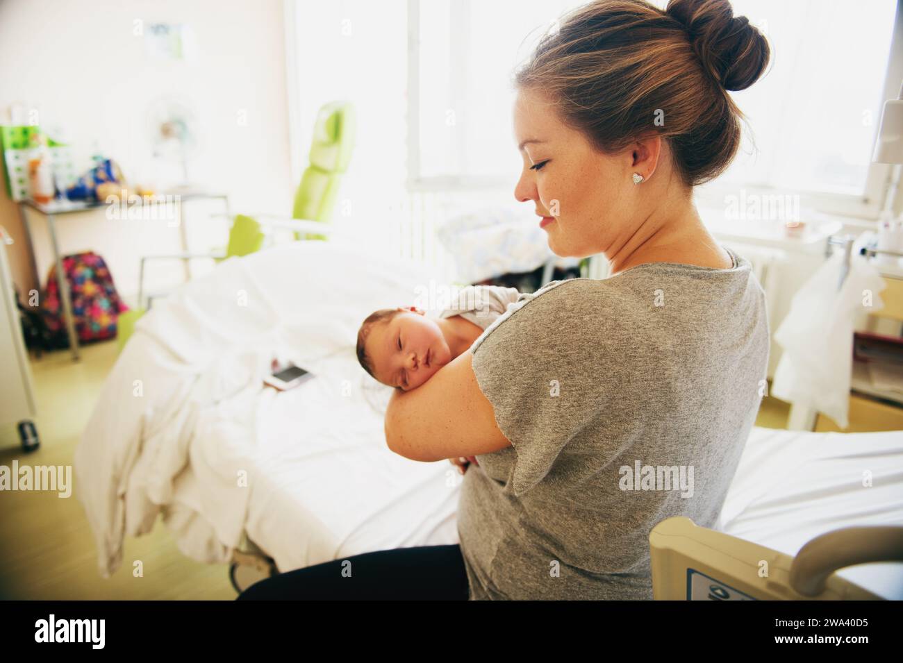 Happy young mother with newborn baby in hospital after giving birth ...