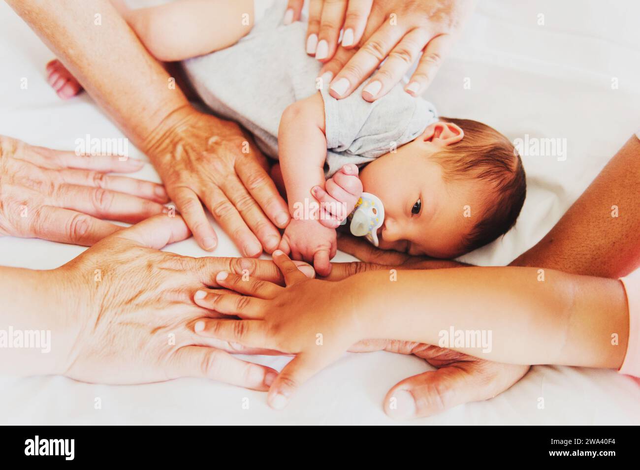 Many hands of family members protecting newborn baby Stock Photo - Alamy