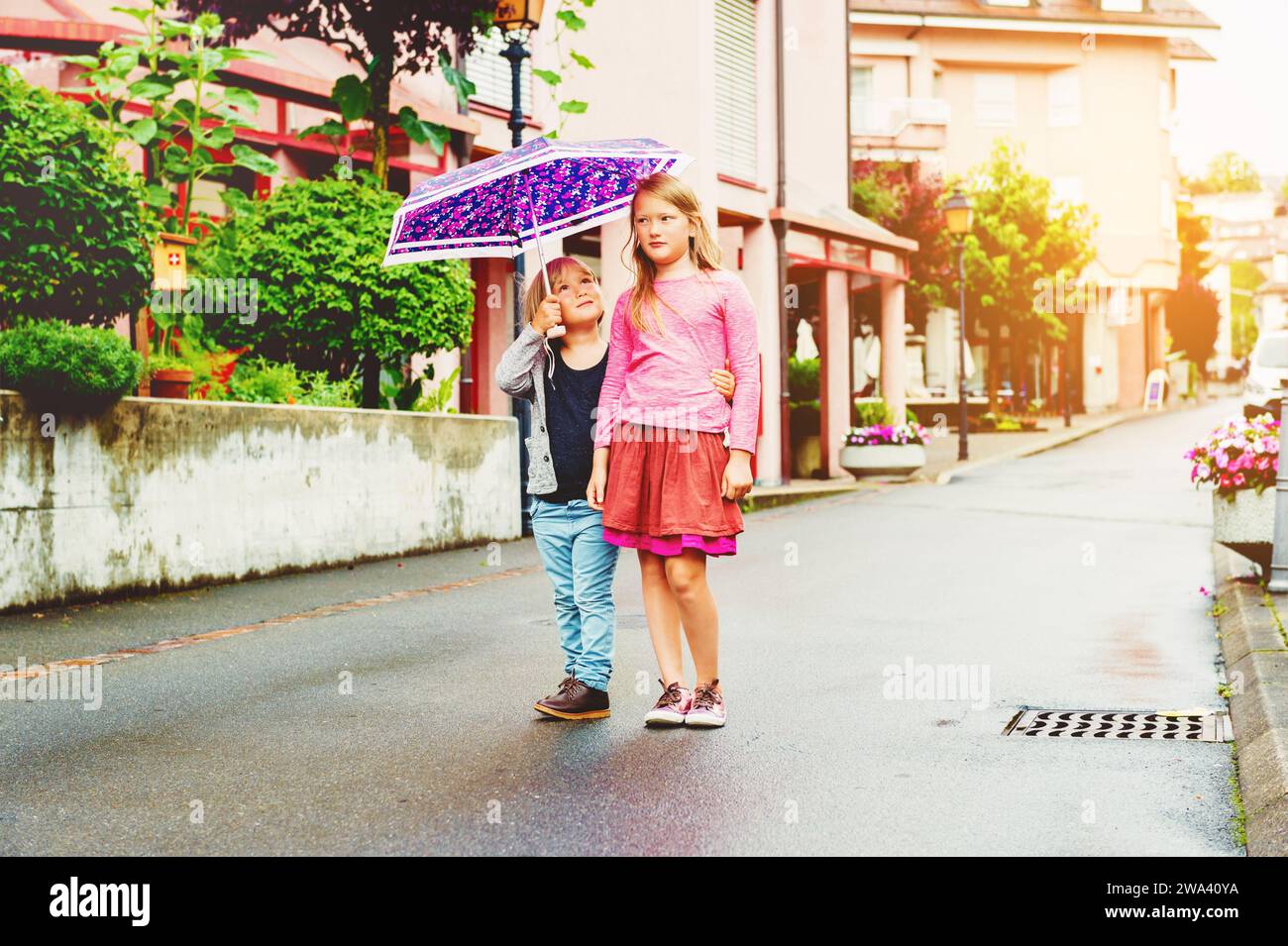 Adorable kids having fun outdoors, playing under the rain Stock Photo ...