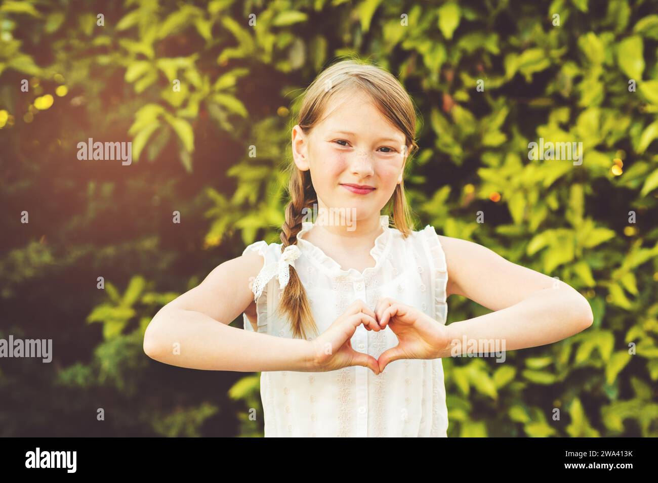 Little girl making heart sign with her hands in the summer garden at ...