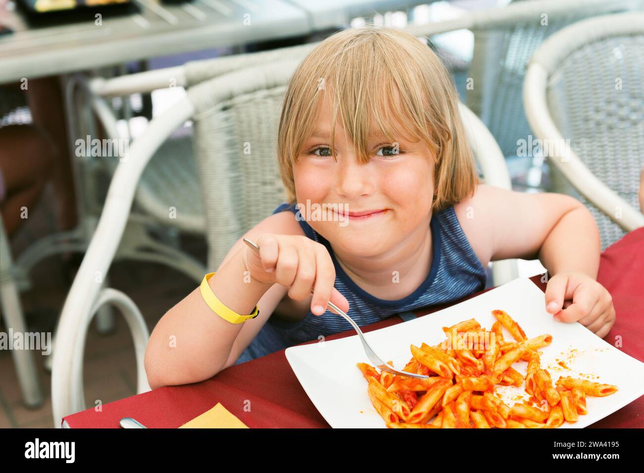 Adorable toddler boy eating pasta with tomatoe sause in restaurant ...