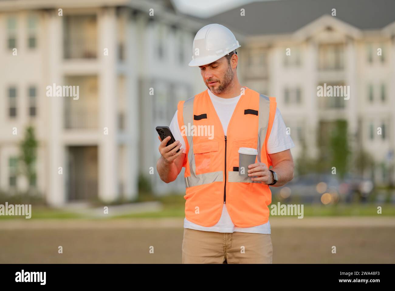 Engineer builder drinking take away coffee using phone on break ...