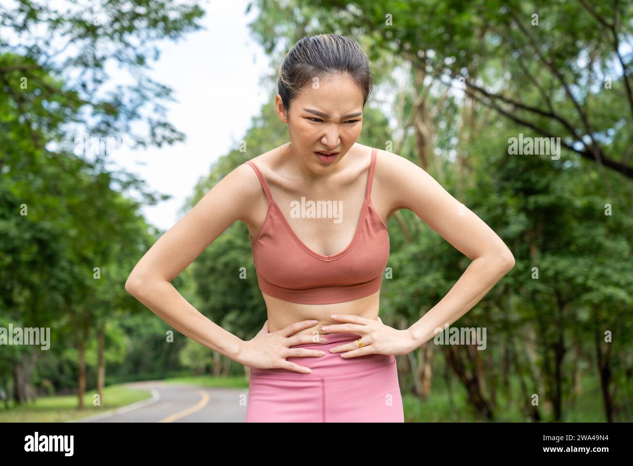 Young atractive Asian woman in fitness clothes with stomach pain ...