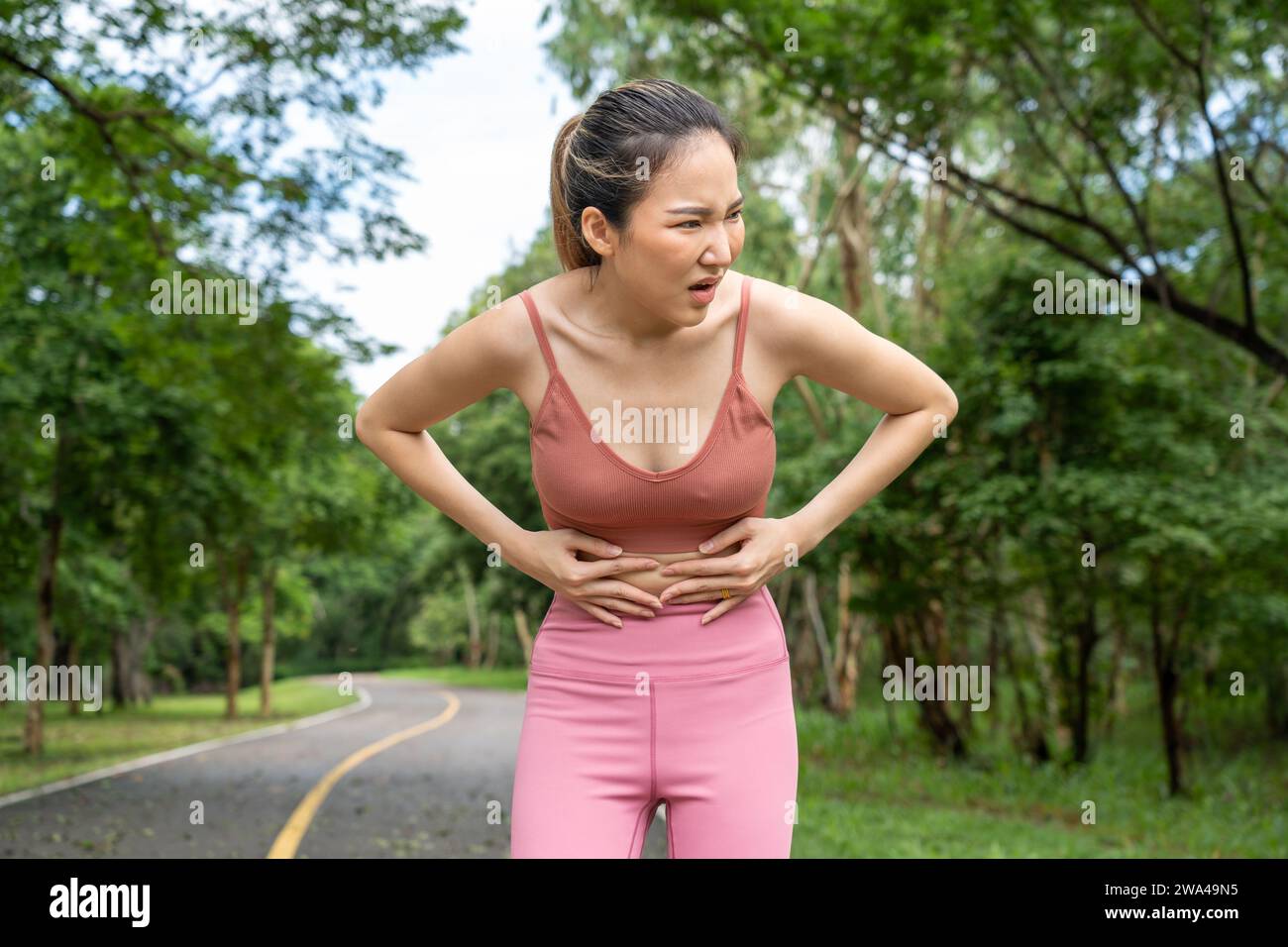 Young atractive Asian woman in fitness clothes with stomach pain ...