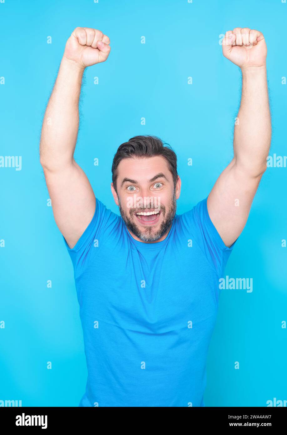 Cheerful excited man celebrating success over studio blue isolated ...