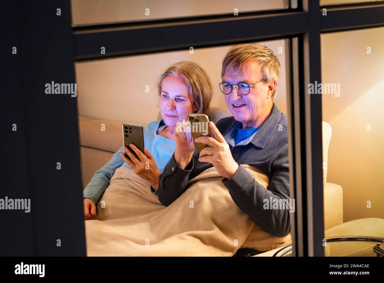 Seniorenpaar surft abends im Internet, beide sitzen mit ihren ...