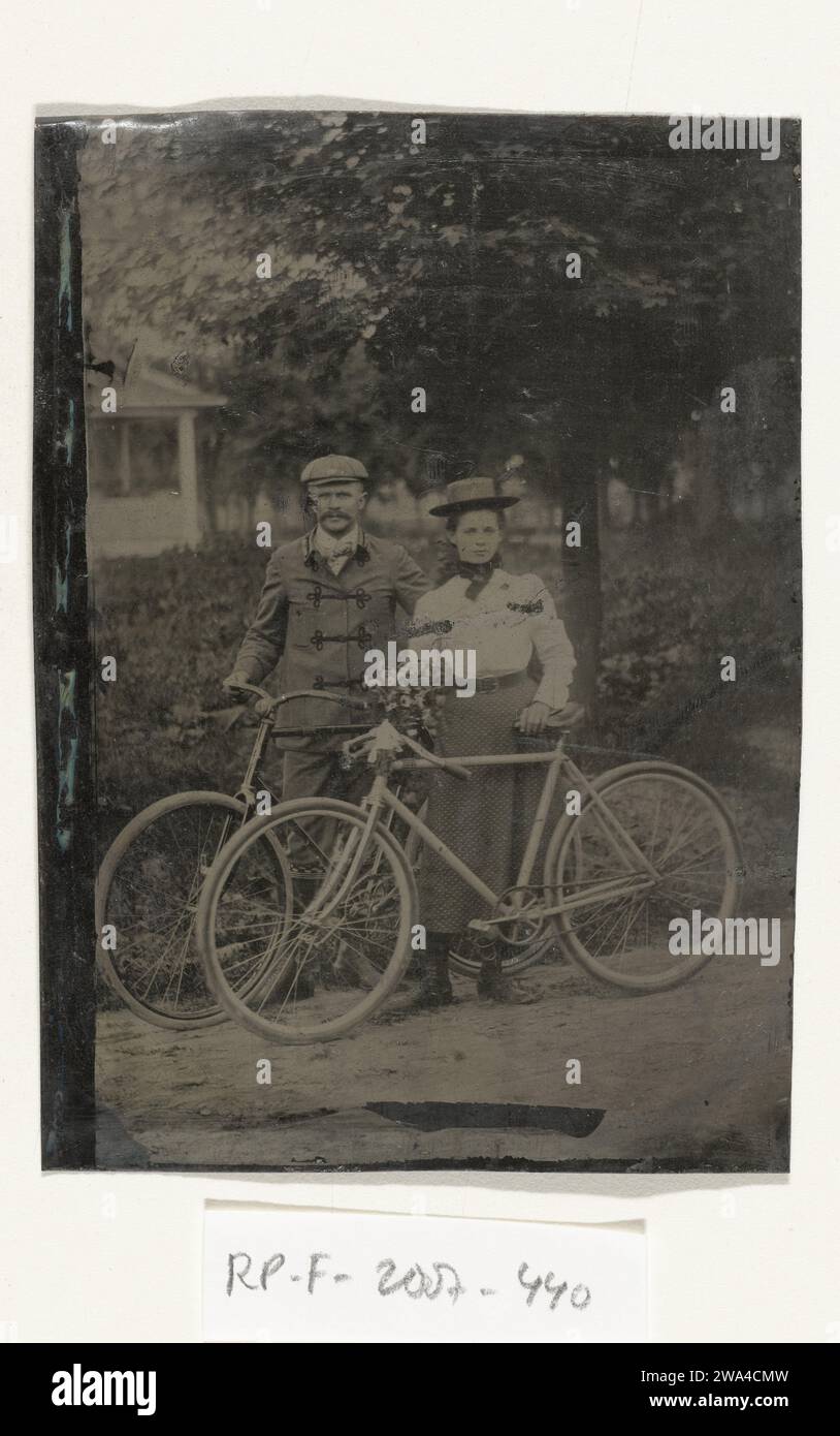 A man and woman standing by their bikes in the open air, with a bunch ...